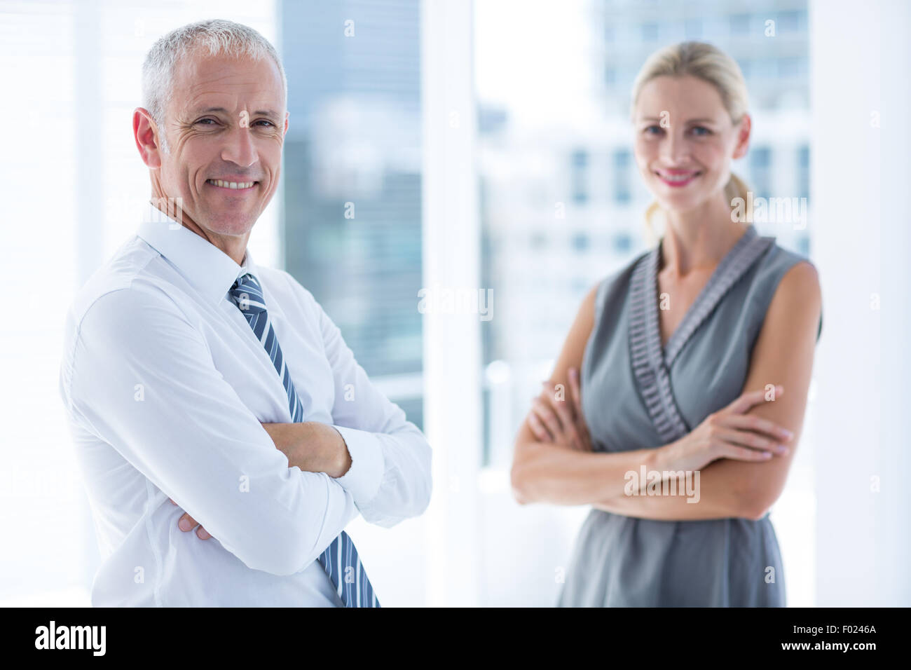 Two business people smiling at the camera in the office Stock Photo - Alamy