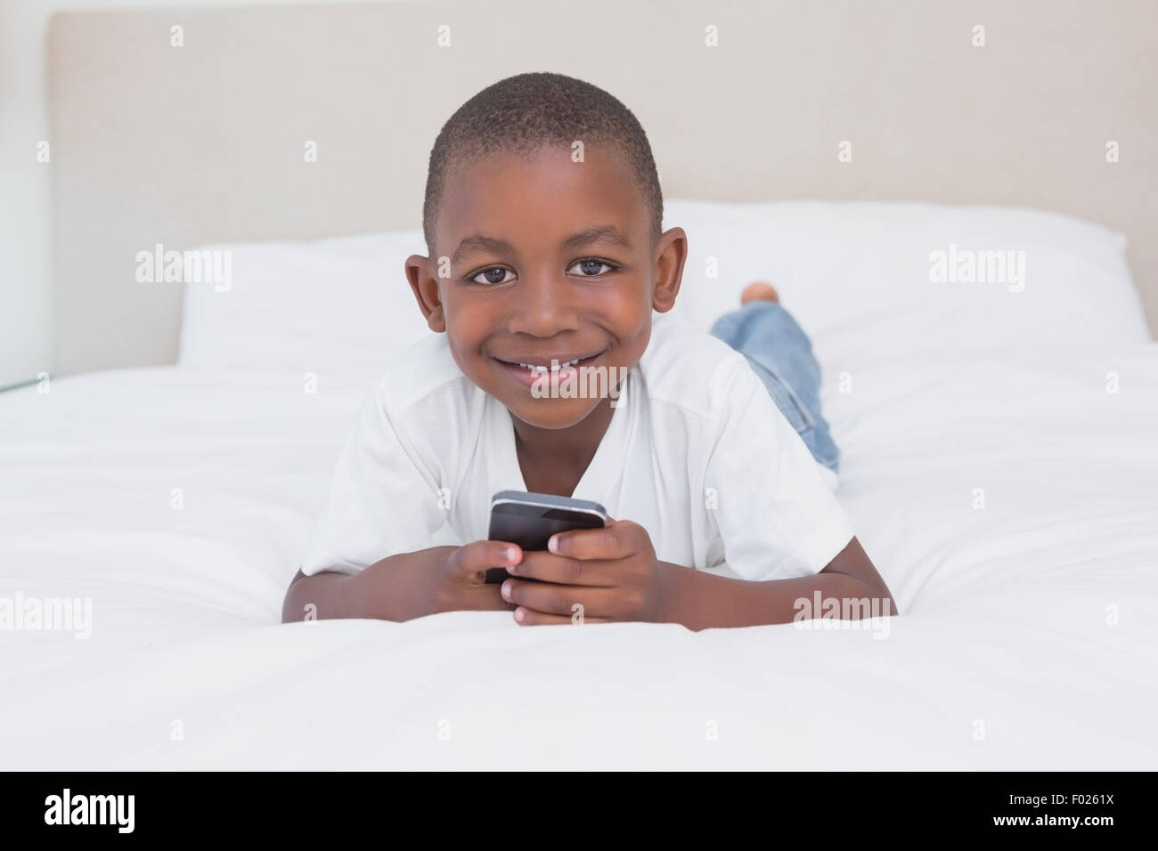 Portrait of a pretty little boy using smartphone in bed Stock Photo - Alamy