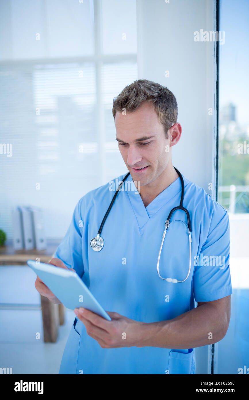 Smiling doctor watching his tablet Stock Photo - Alamy