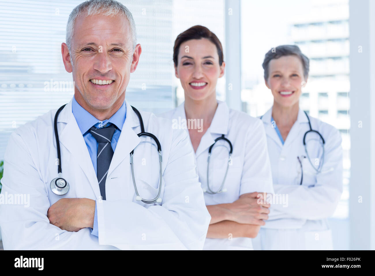 Portrait of three smiling medical colleagues with arms crossed Stock ...