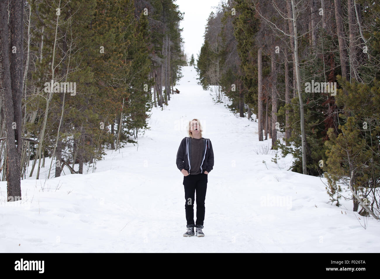 Young man standing in snow, laughing Stock Photo - Alamy