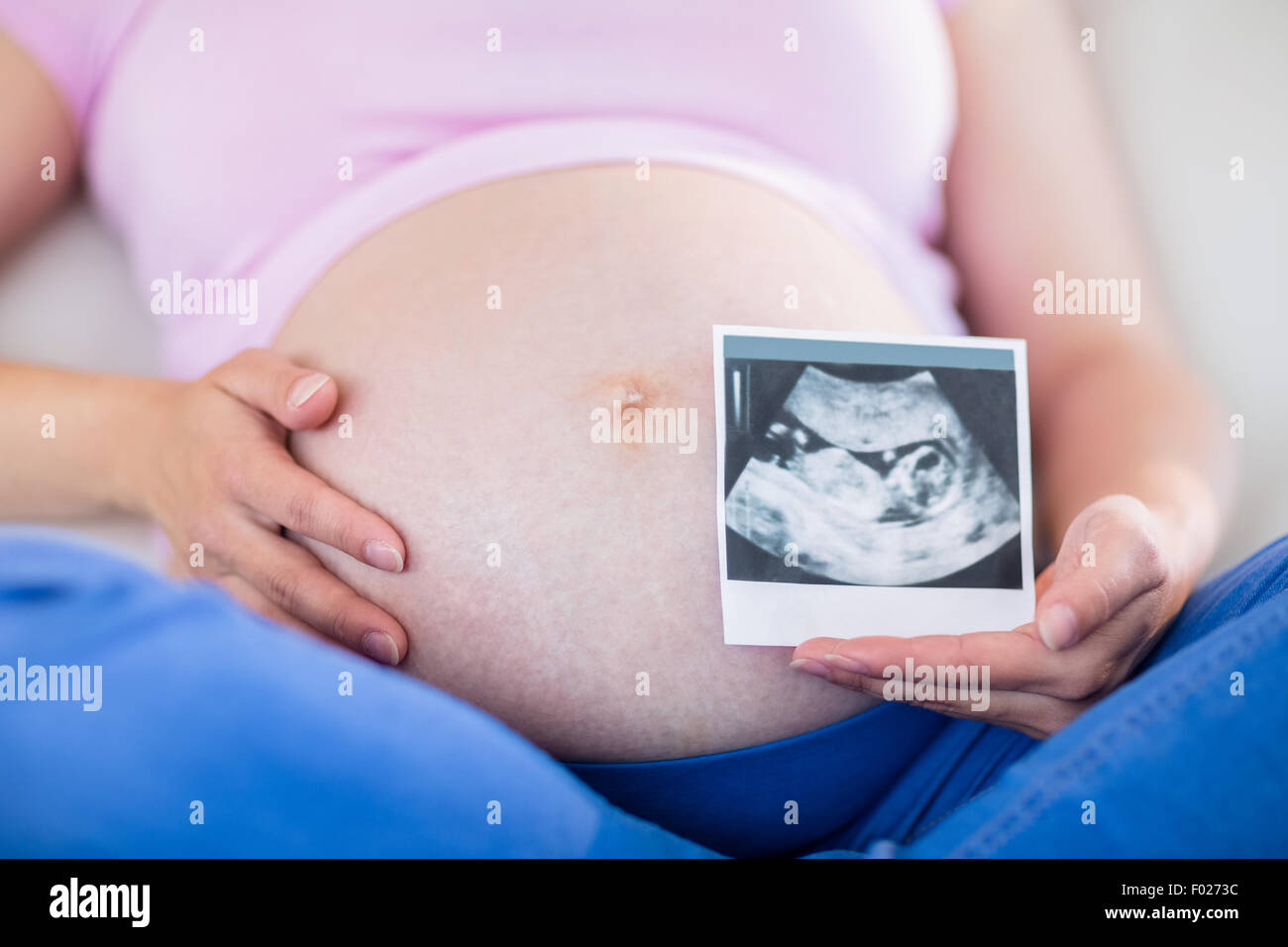 Pregnant woman showing ultrasound scans and touching her belly Stock ...
