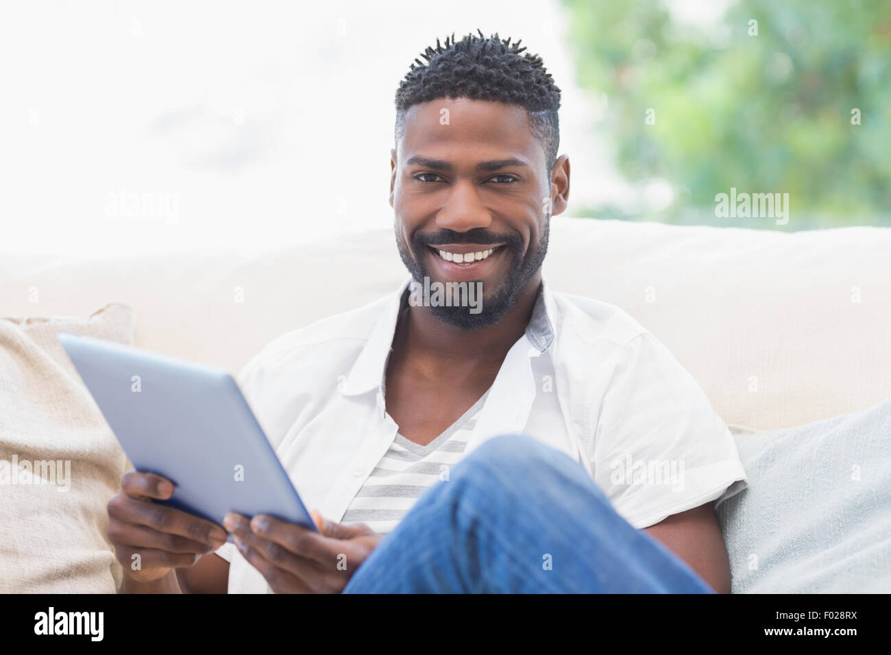 Man using his tablet on couch Stock Photo - Alamy