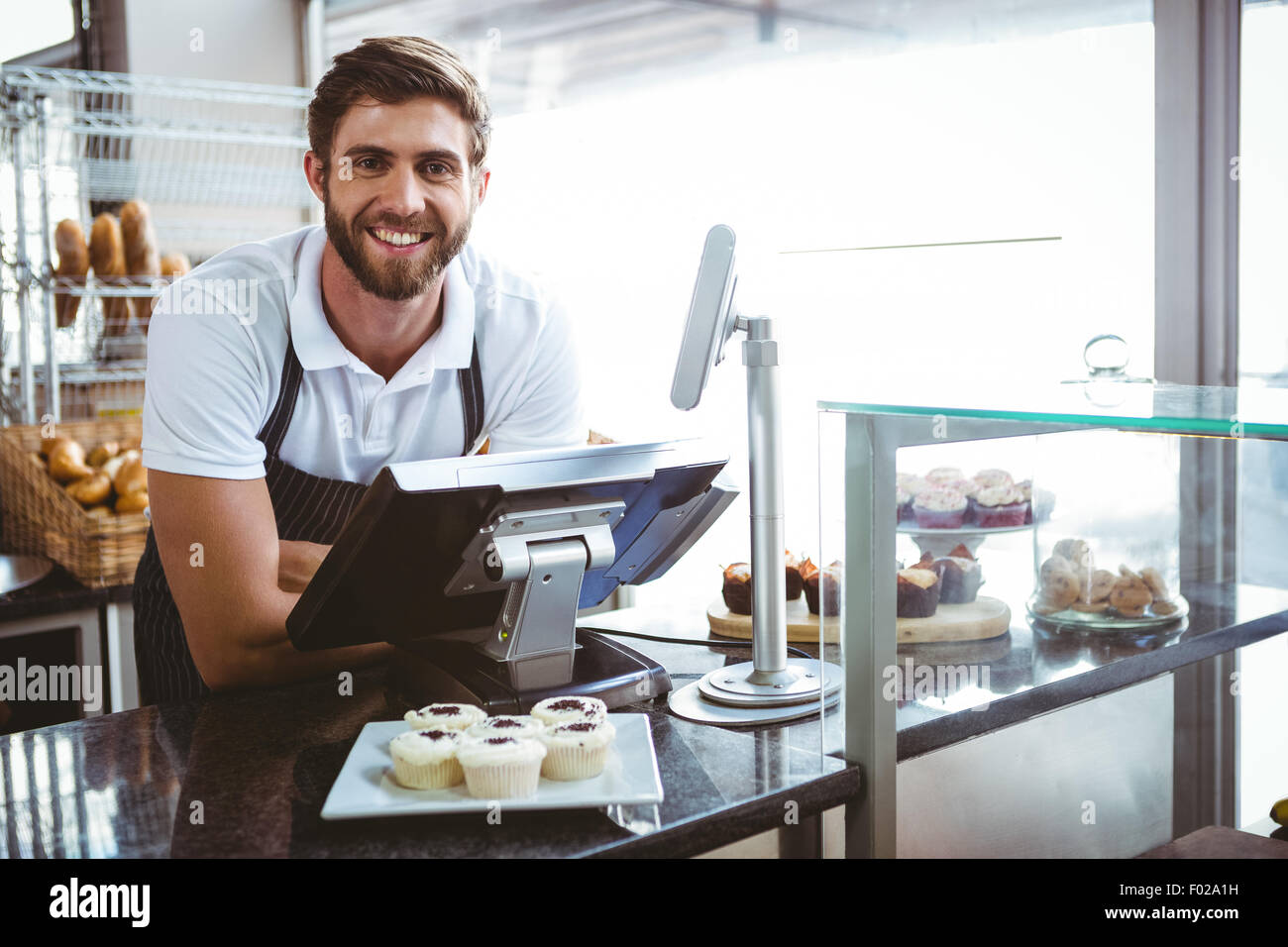 Smiling worker posing behind the counter Stock Photo - Alamy