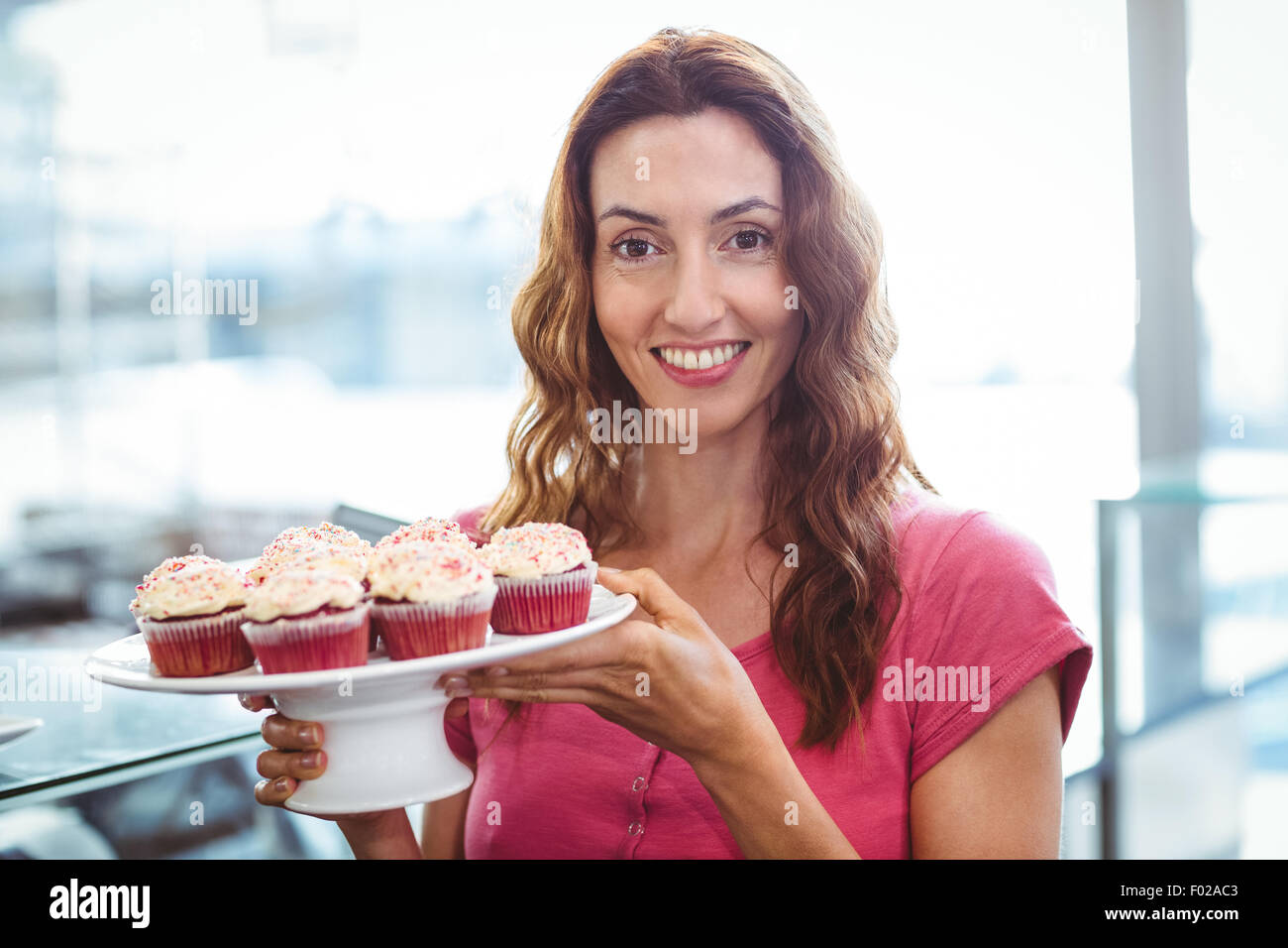Pretty brunette showing plate of pastries Stock Photo - Alamy