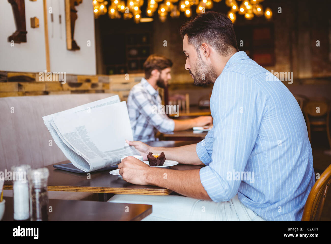 Businessman reading a newspaper while eating Stock Photo - Alamy