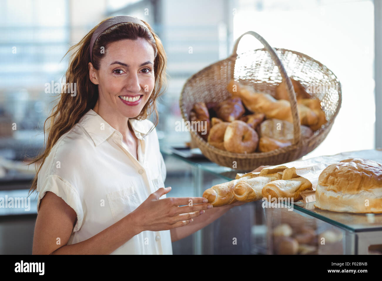 Pretty brunette smiling at camera and holding loaf of bread Stock Photo ...