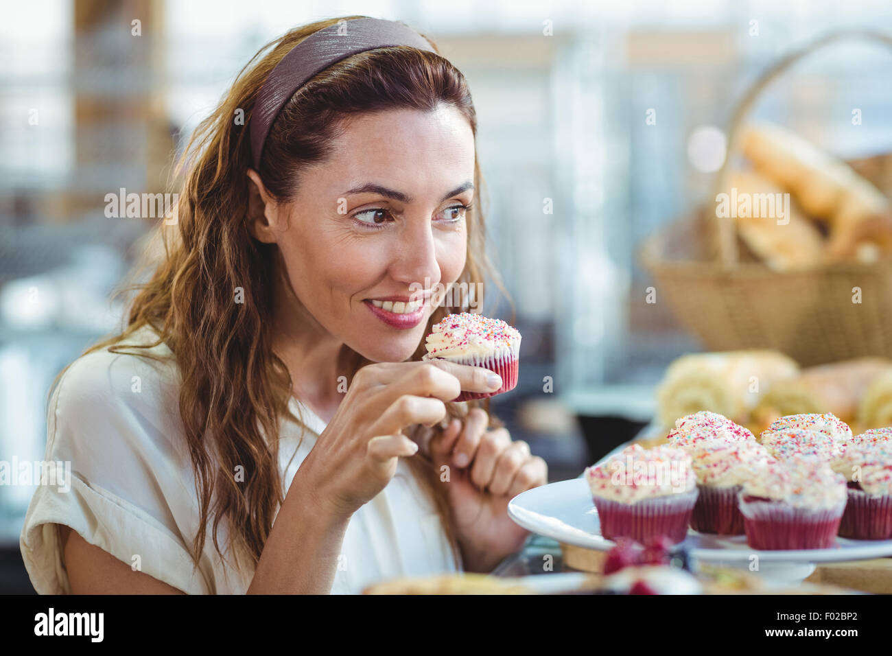 Pretty brunette holding and smelling cupcake Stock Photo - Alamy