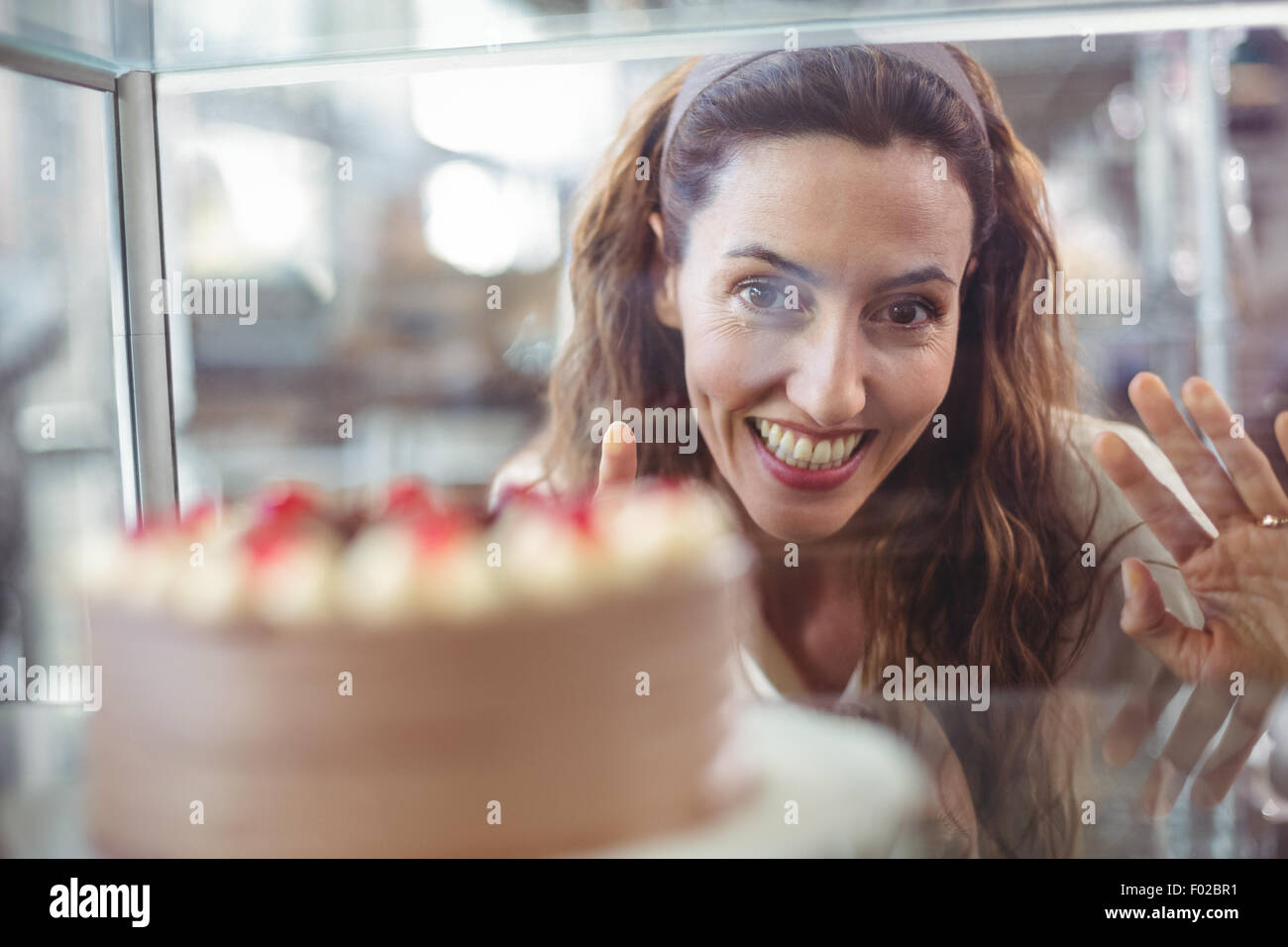 Pretty brunette looking at chocolate cake through the glass Stock Photo ...