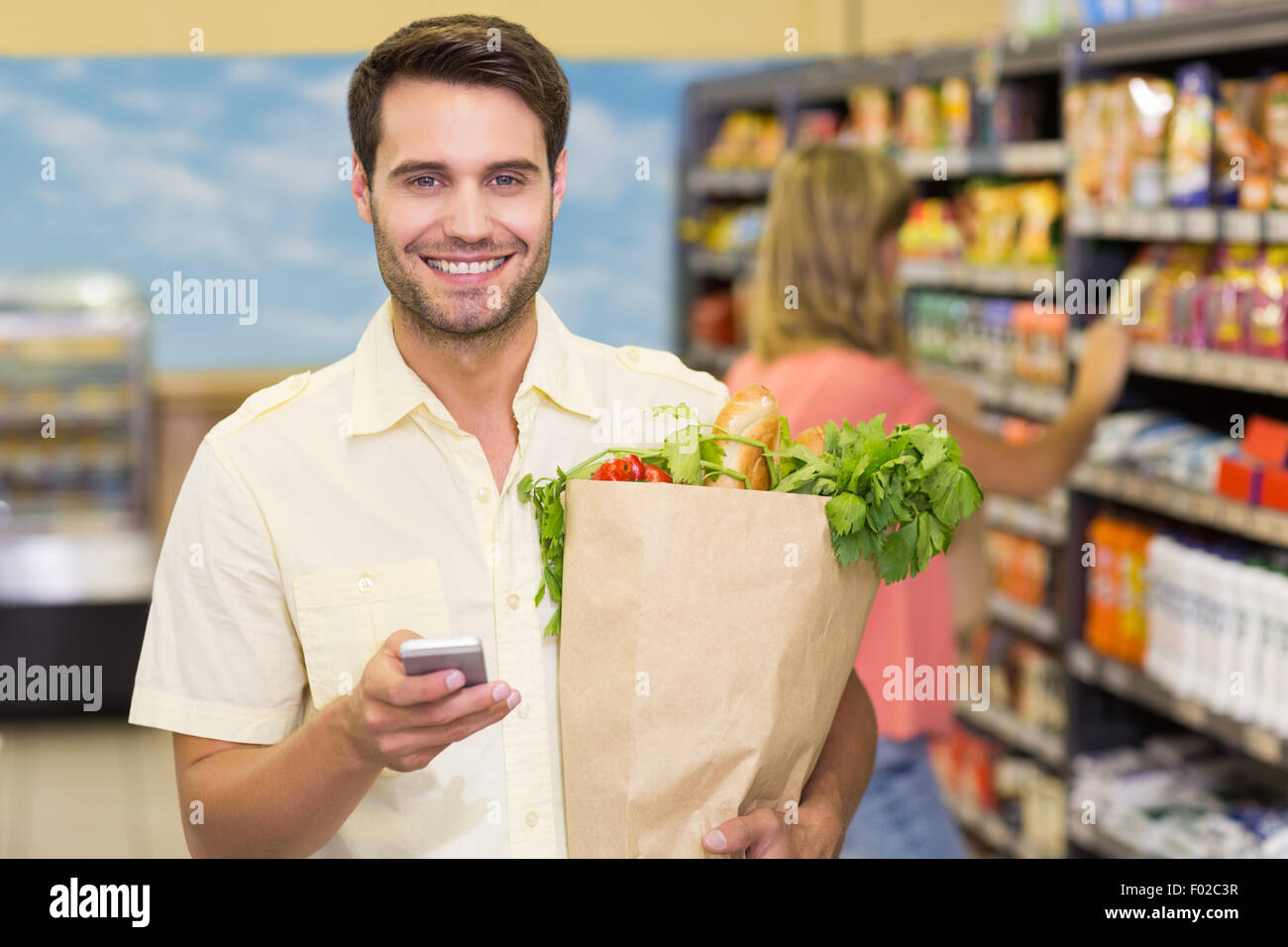 Portrait of smiling handsome man buying food products and using his ...