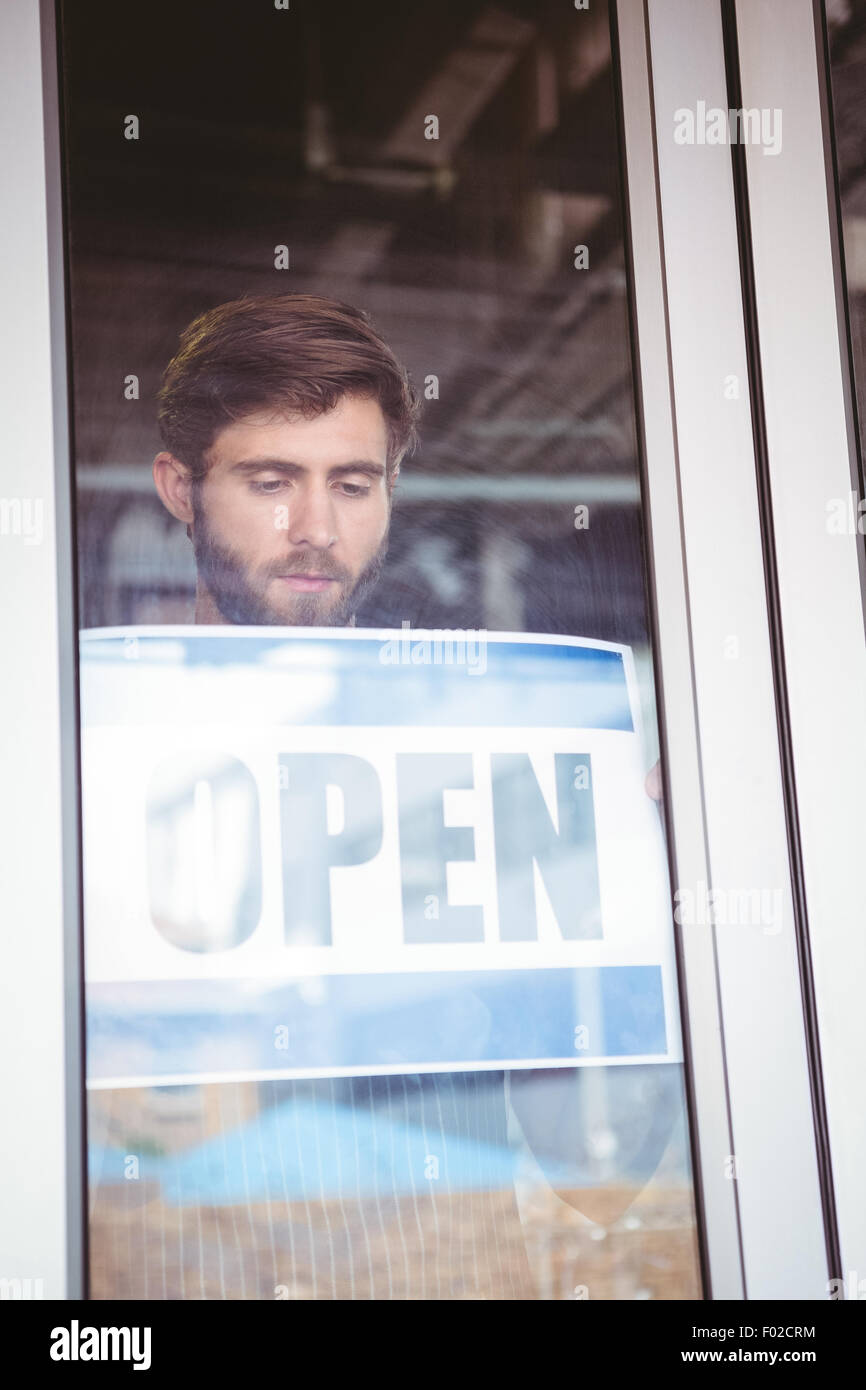 Smiling worker putting up open sign Stock Photo - Alamy