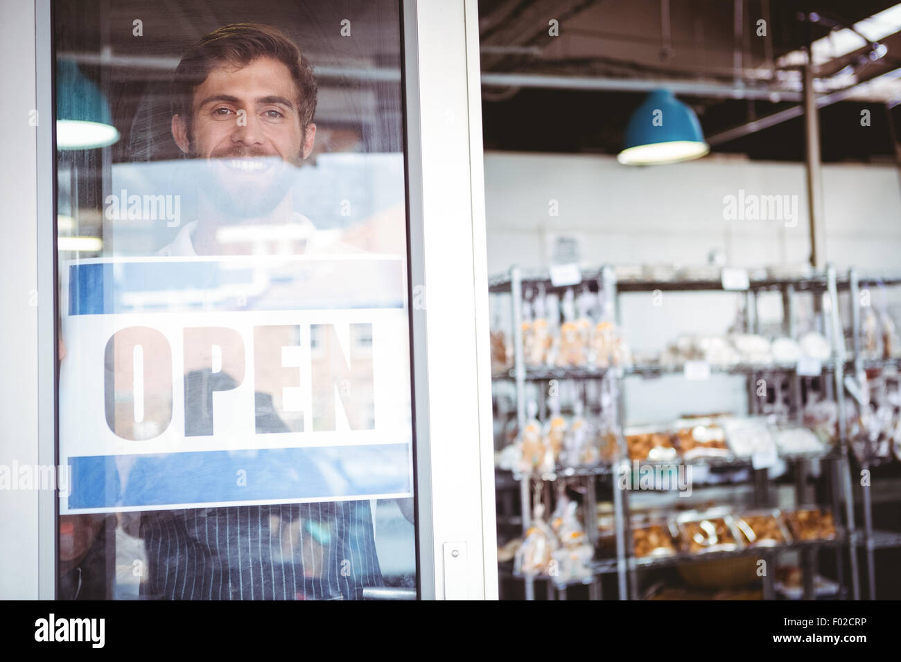 Smiling worker putting up open sign Stock Photo - Alamy