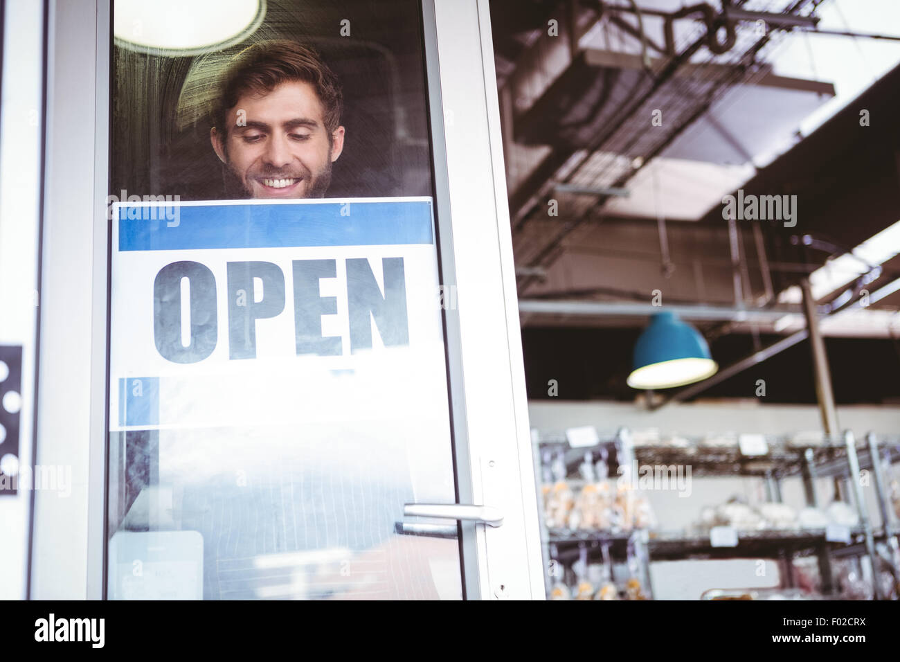 Smiling worker putting up open sign Stock Photo - Alamy