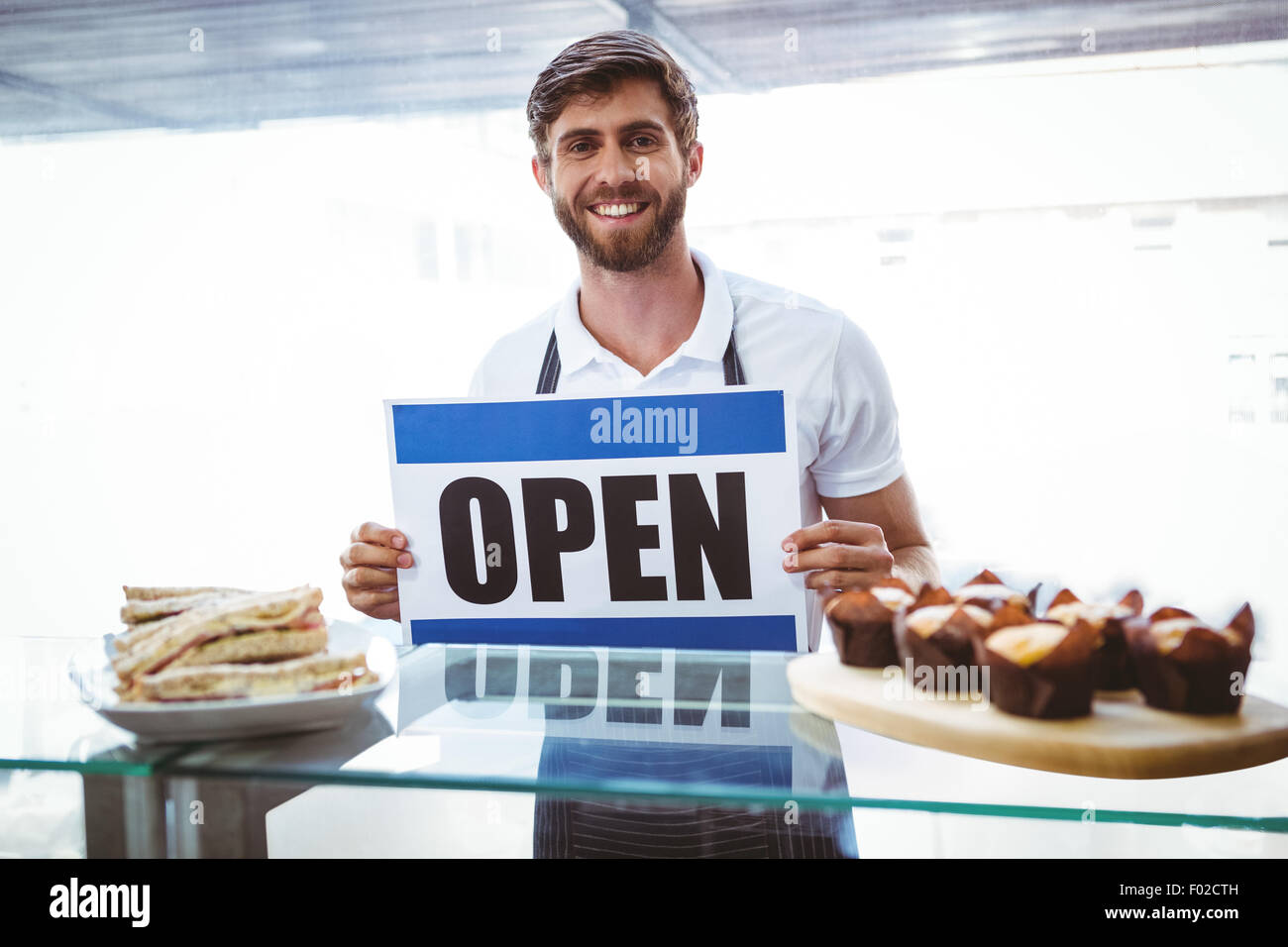 Smiling worker putting up open sign Stock Photo - Alamy