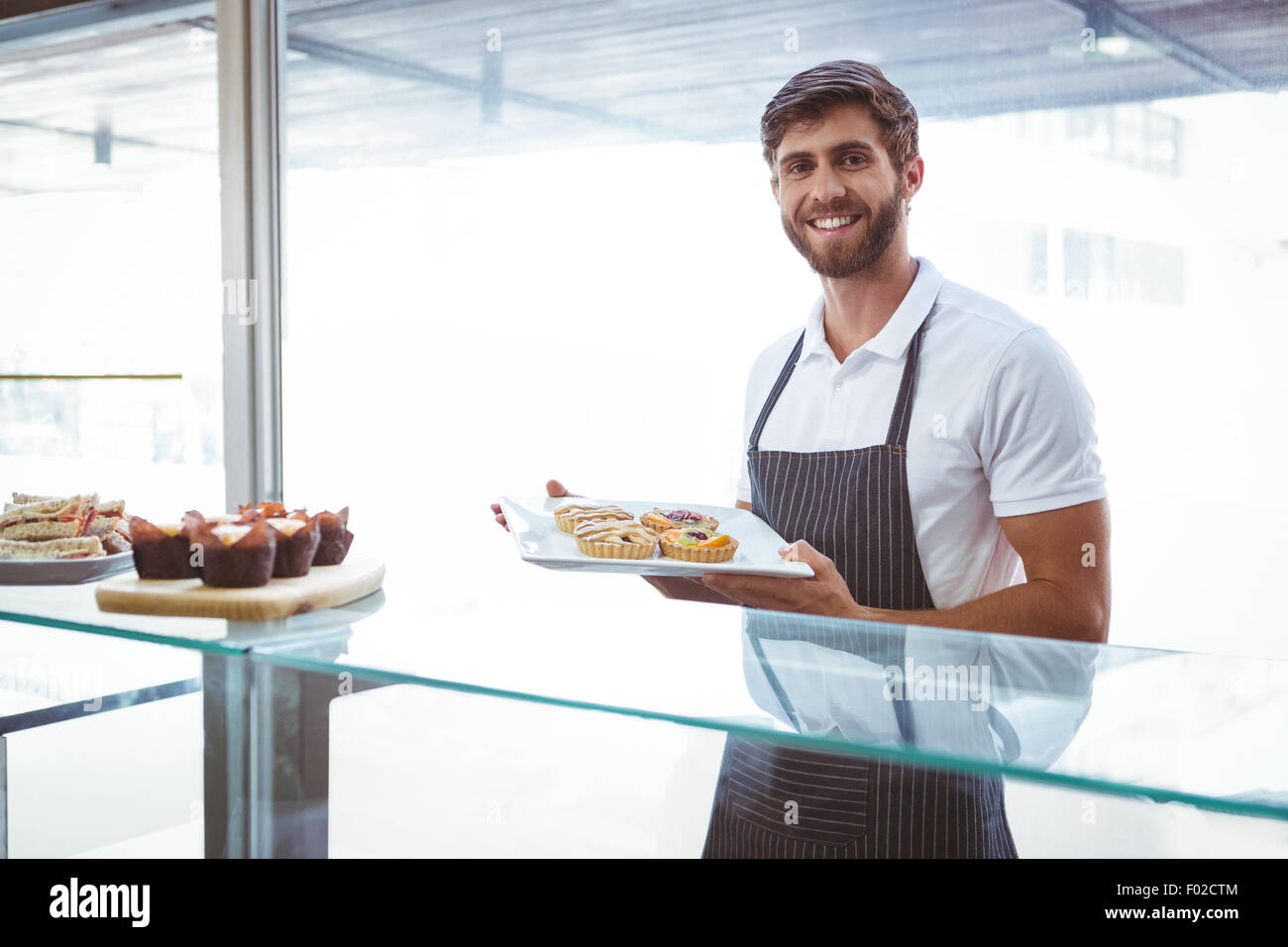Smiling worker posing behind the counter Stock Photo - Alamy