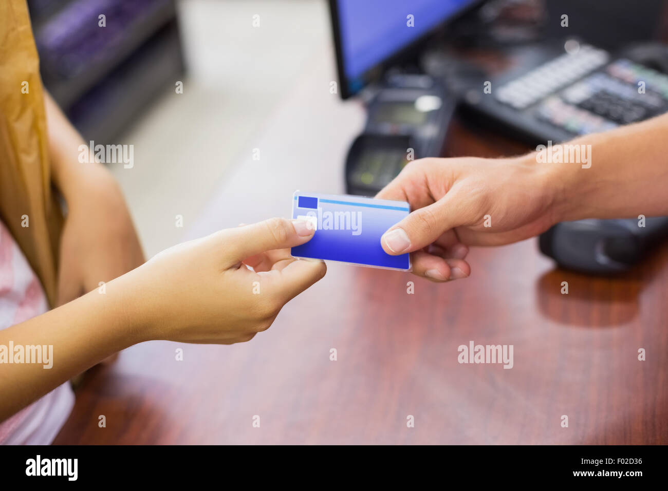 Smiling woman at cash register paying with credit card Stock Photo - Alamy