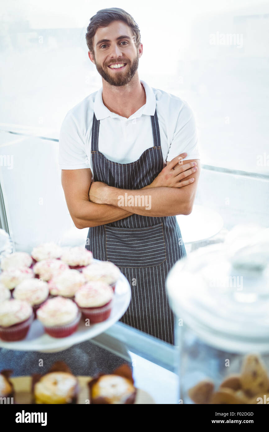 Smiling worker posing behind the counter arm crossed Stock Photo - Alamy