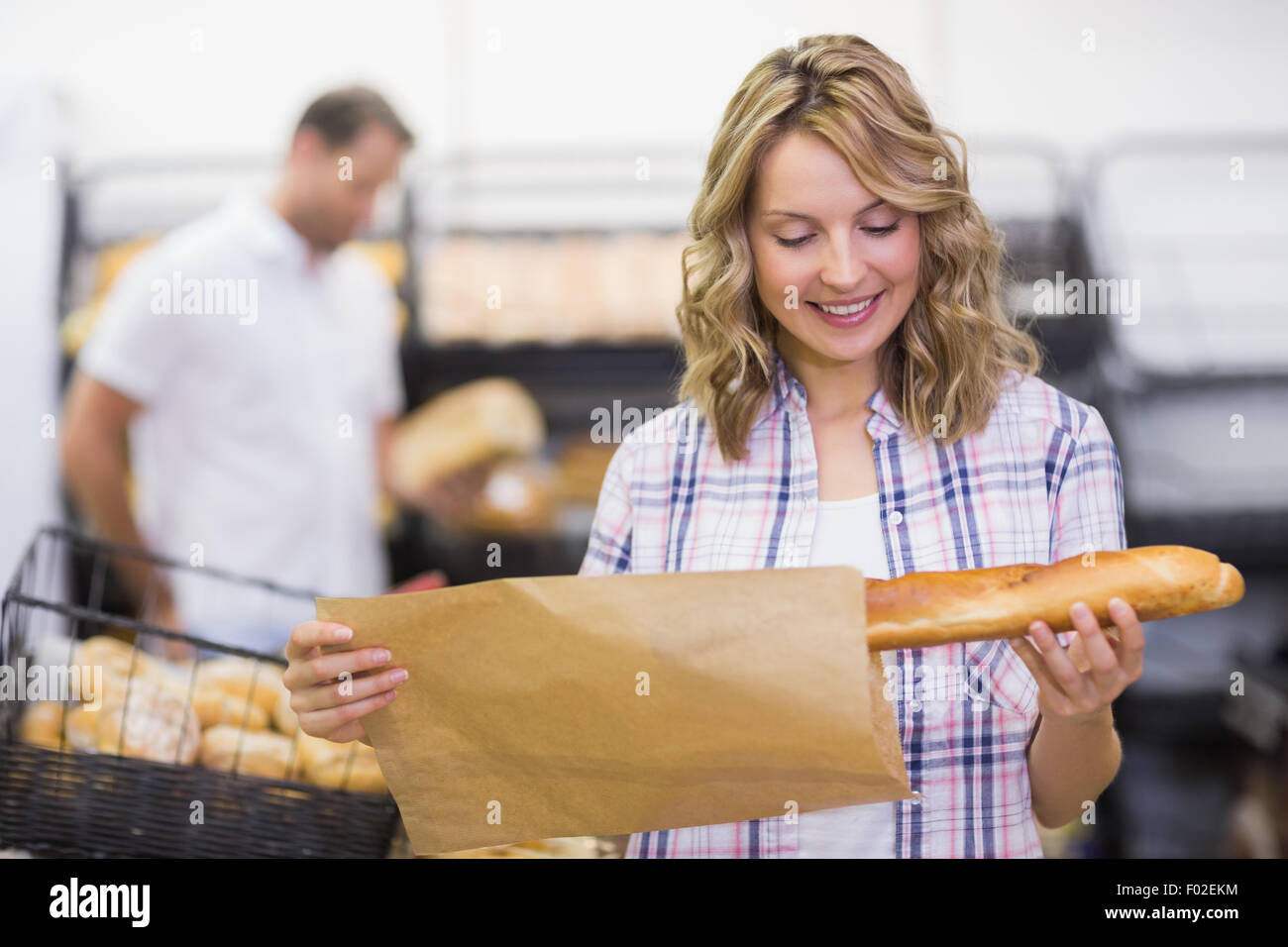 Smiling blonde woman looking at a bread Stock Photo - Alamy