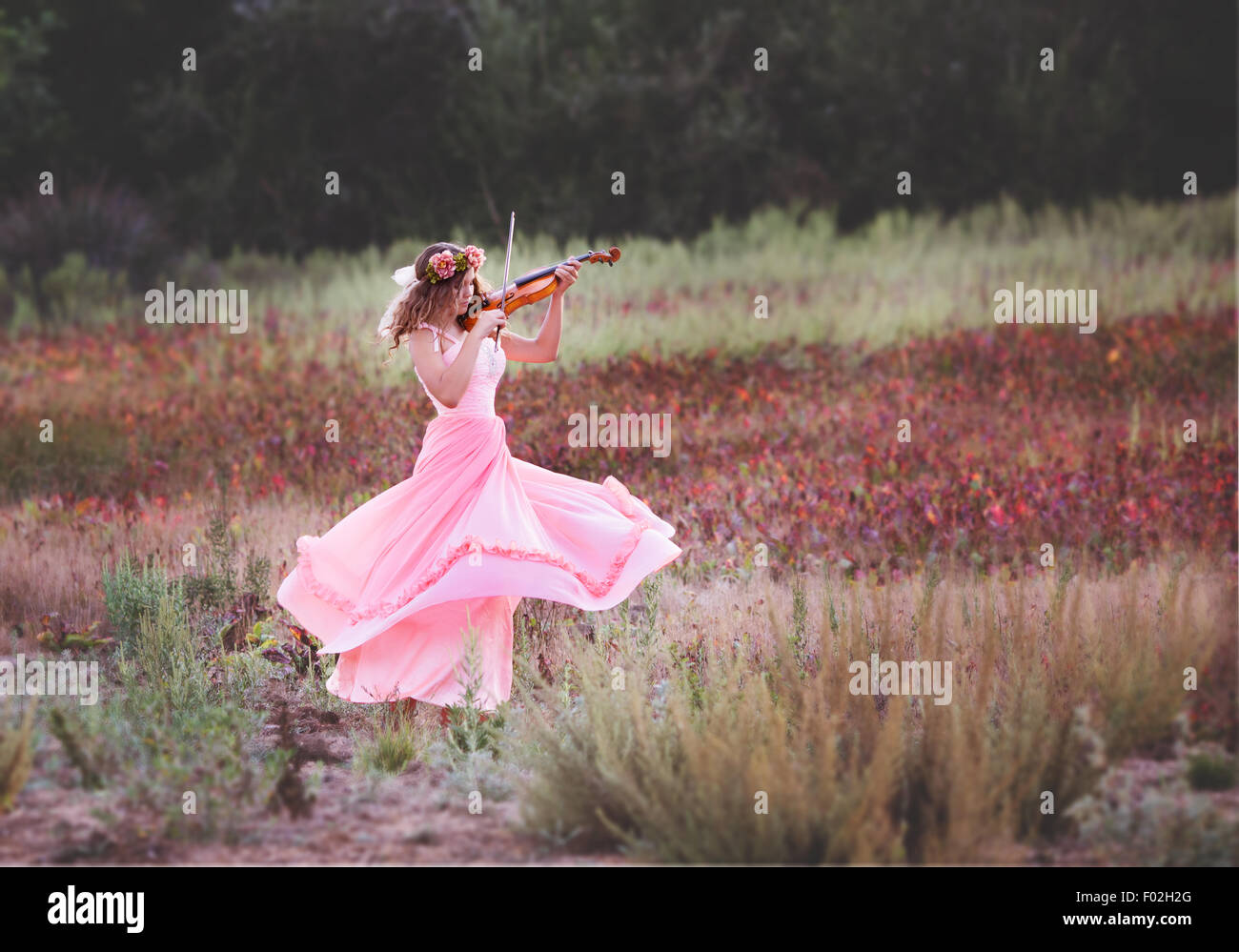 Girl dancing in a field whilst playing a violin Stock Photo - Alamy