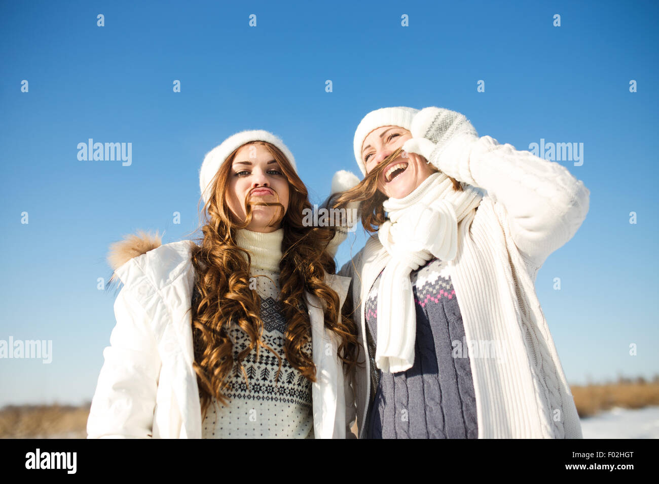 Two girlfriends have fun and enjoy fresh snow at beautiful winter day ...