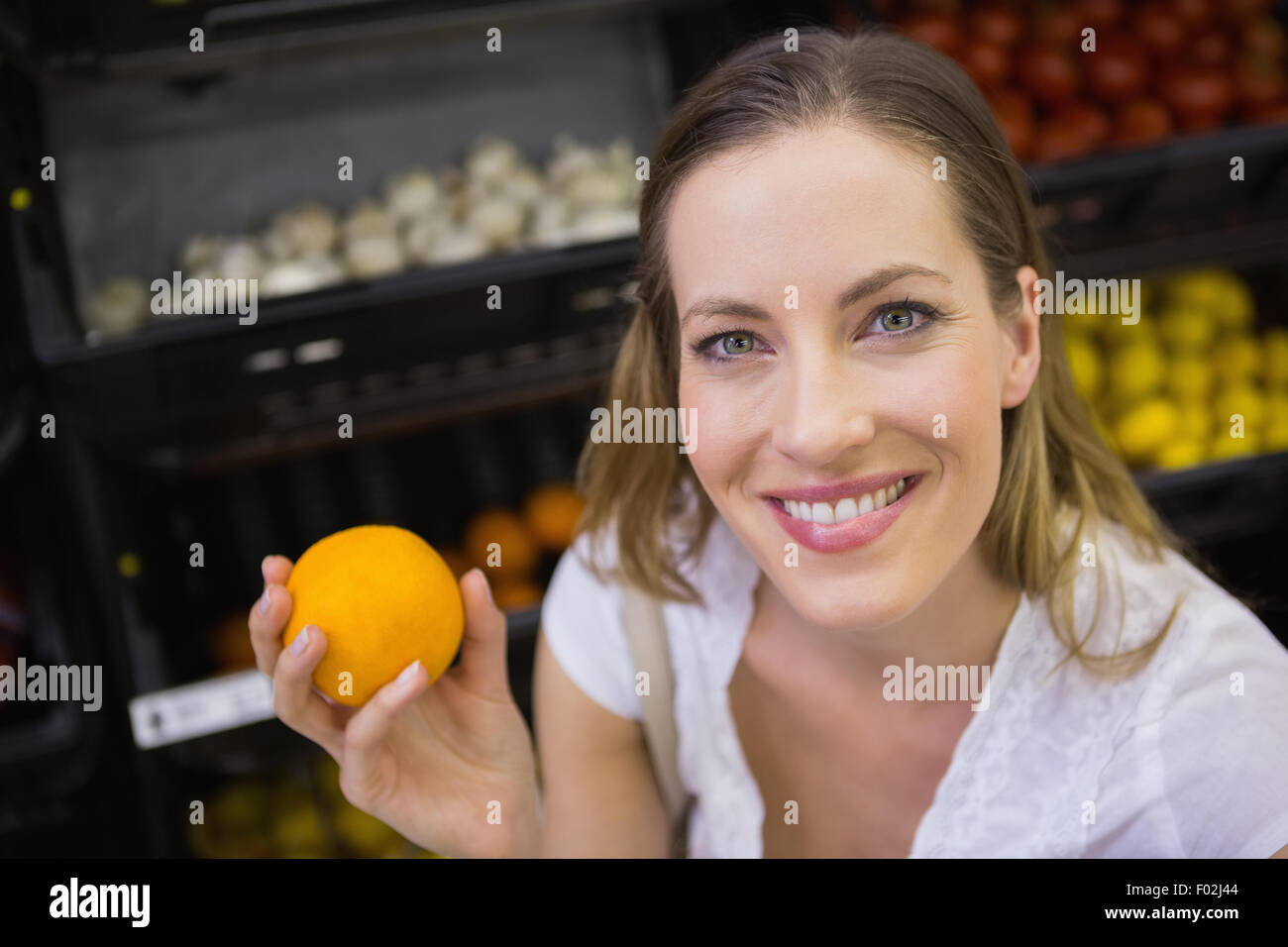 Smiling pretty blonde woman buying oranges Stock Photo - Alamy