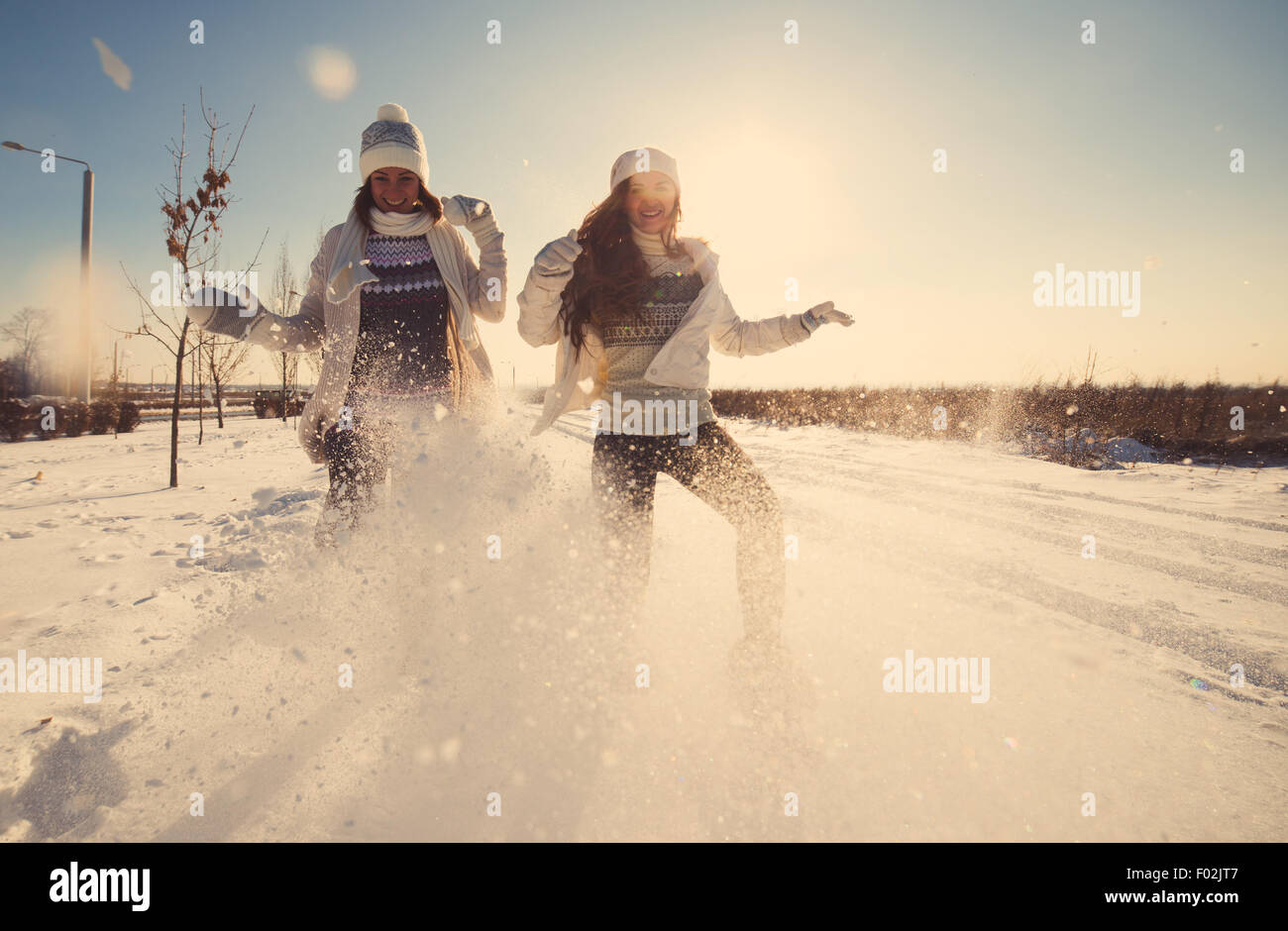 Two girlfriends have fun and enjoy fresh snow at beautiful winter day ...