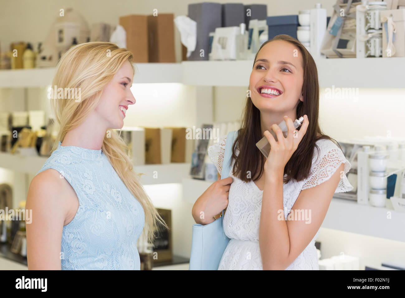 Happy beautiful women spraying perfume Stock Photo - Alamy