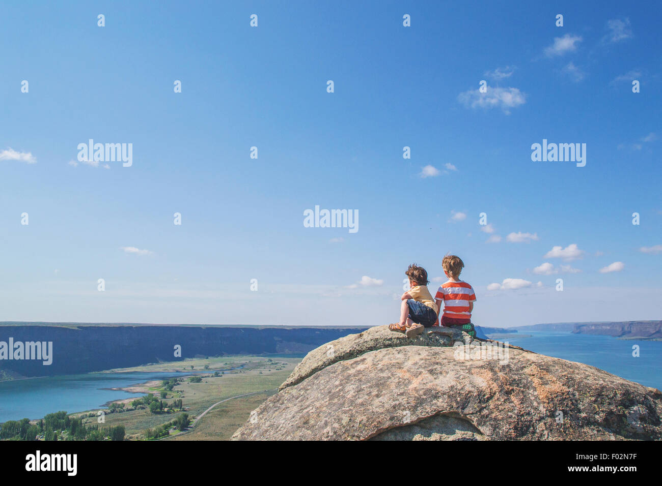 Two boys sitting on rock Stock Photo - Alamy