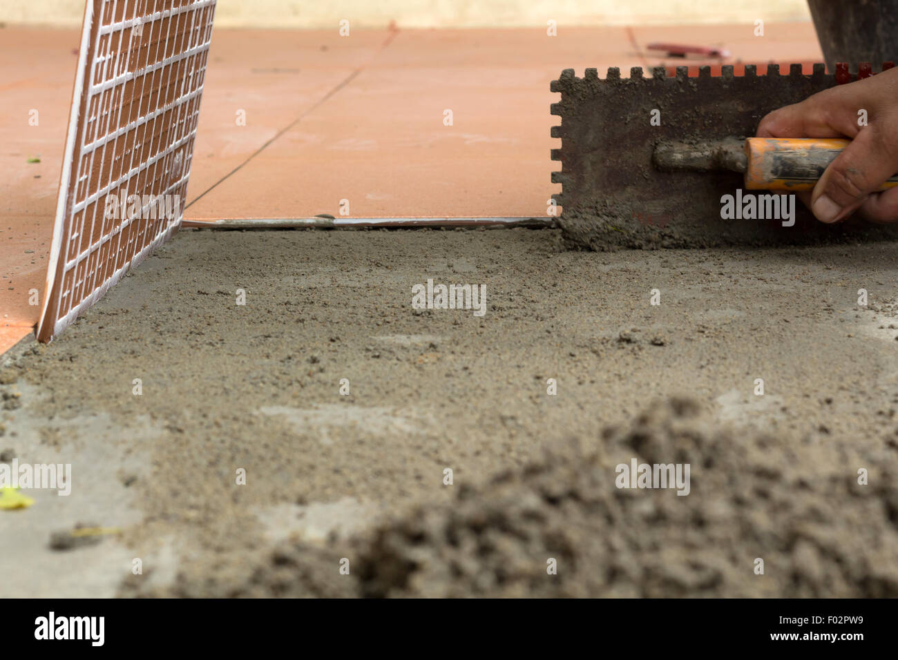 a tiler at work. bonding of floor tile with tile adhesive and filler ...