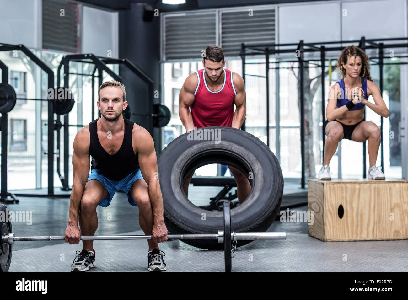 Serious three muscular people lifting and jumping Stock Photo - Alamy