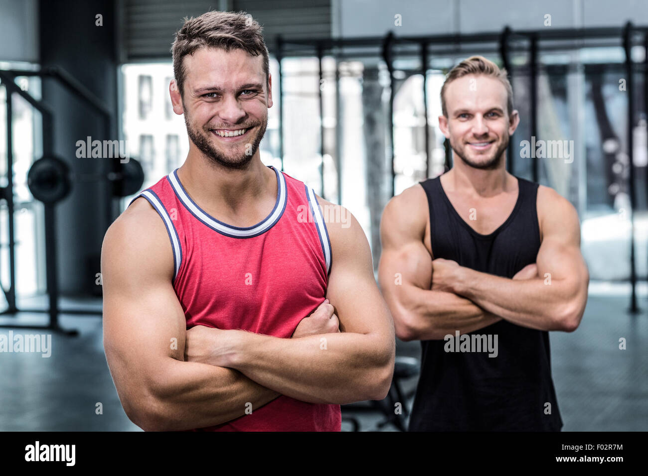 Two smiling muscular men with arms crossed Stock Photo - Alamy
