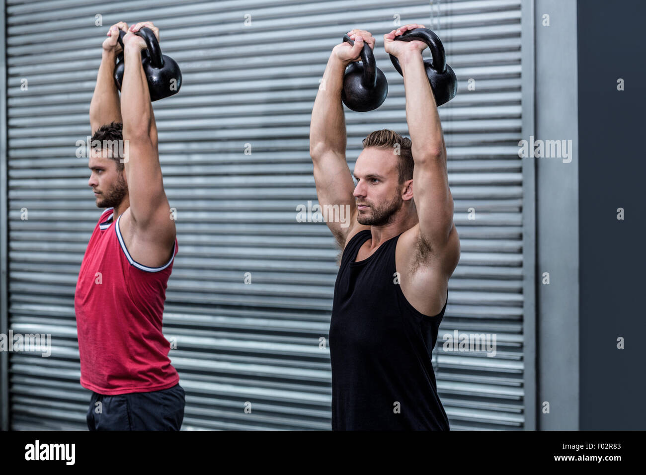 Muscular men lifting a kettle bell Stock Photo - Alamy