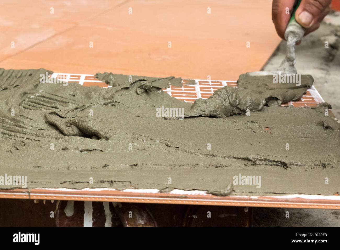 a tiler at work. bonding of floor tile with tile adhesive and filler ...