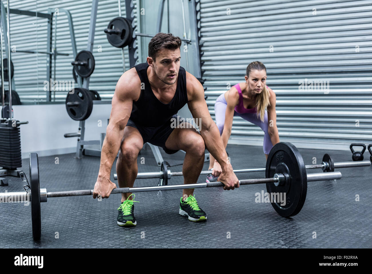 Muscular couple lifting weight together Stock Photo - Alamy