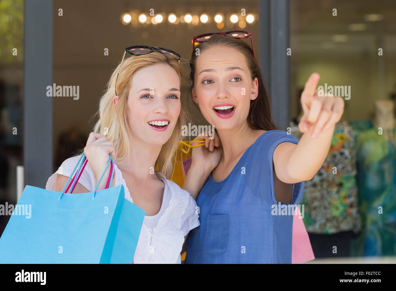 Smiling girls friends pointing away Stock Photo - Alamy
