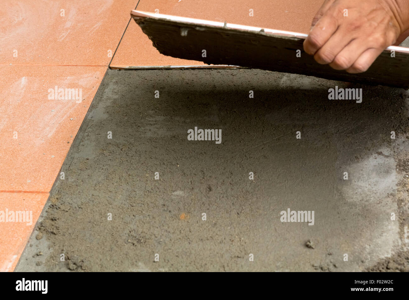 a tiler at work. bonding of floor tile with tile adhesive and filler ...