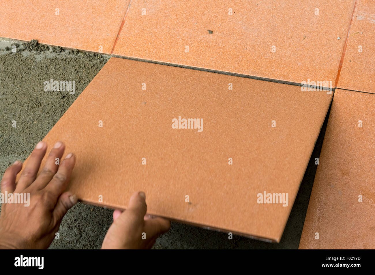 a tiler at work. bonding of floor tile with tile adhesive and filler ...