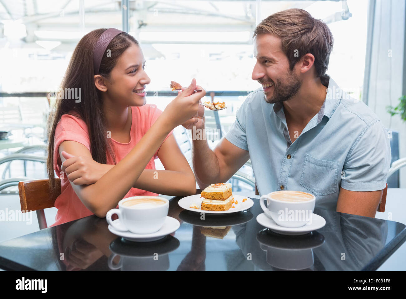 Young happy couple eating cake together Stock Photo - Alamy