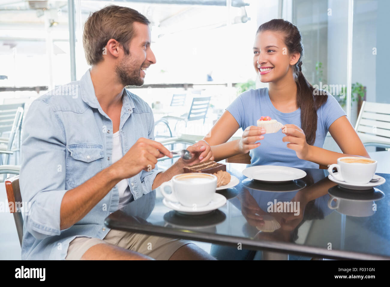 Young happy couple eating cake together Stock Photo - Alamy