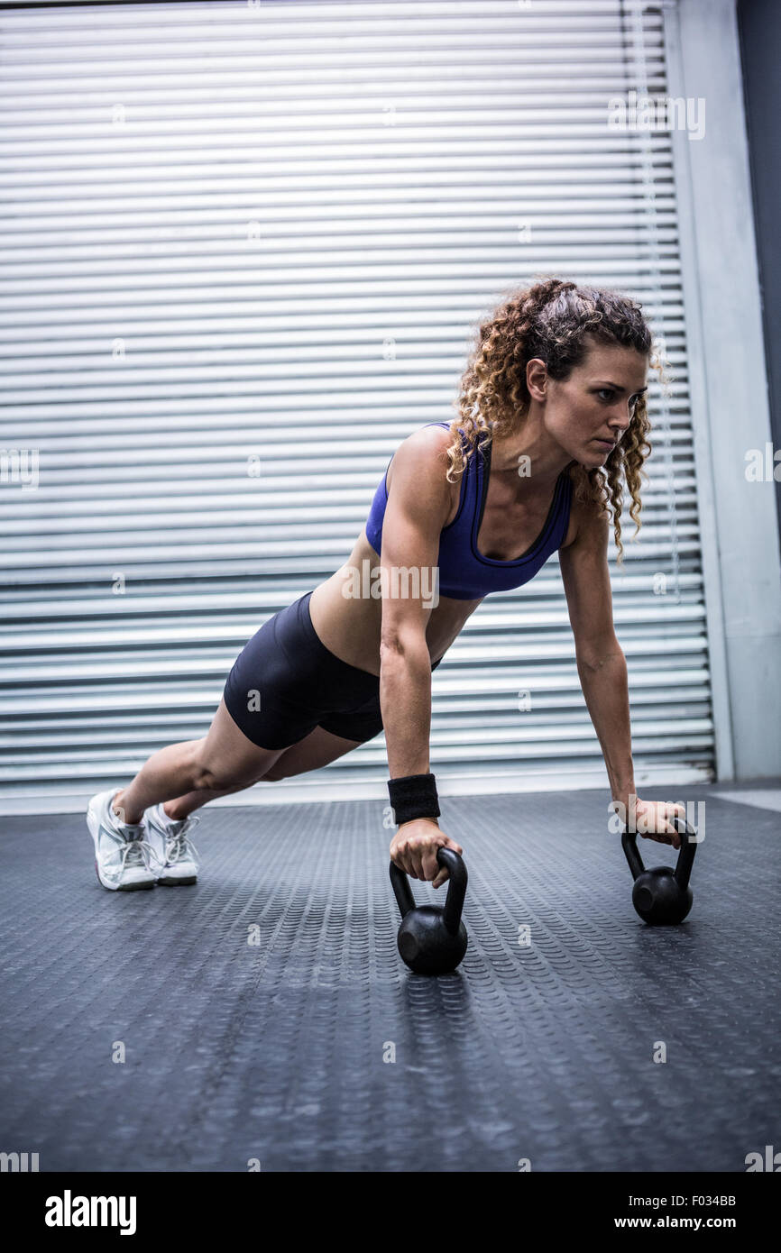 Muscular woman doing push-ups with kettlebells Stock Photo - Alamy