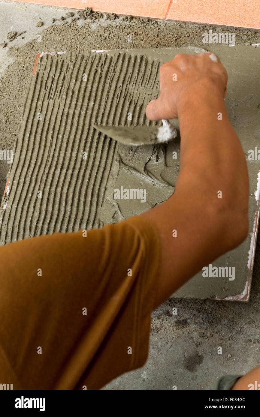 a tiler at work. bonding of floor tile with tile adhesive and filler ...