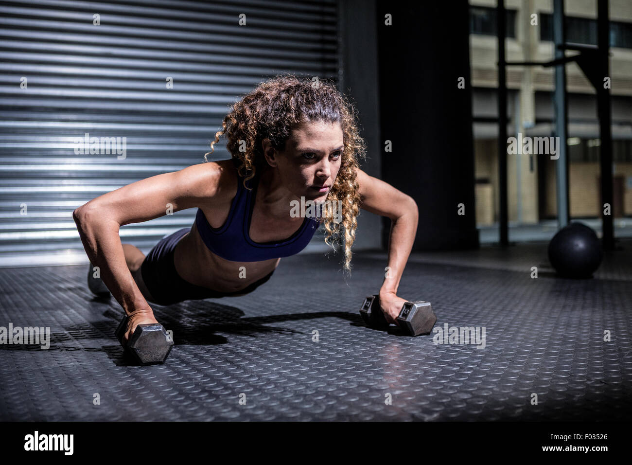 Muscular woman doing push-ups with kettlebells Stock Photo - Alamy