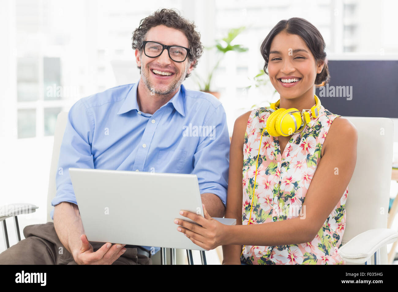 Casual business partners holding laptop Stock Photo - Alamy