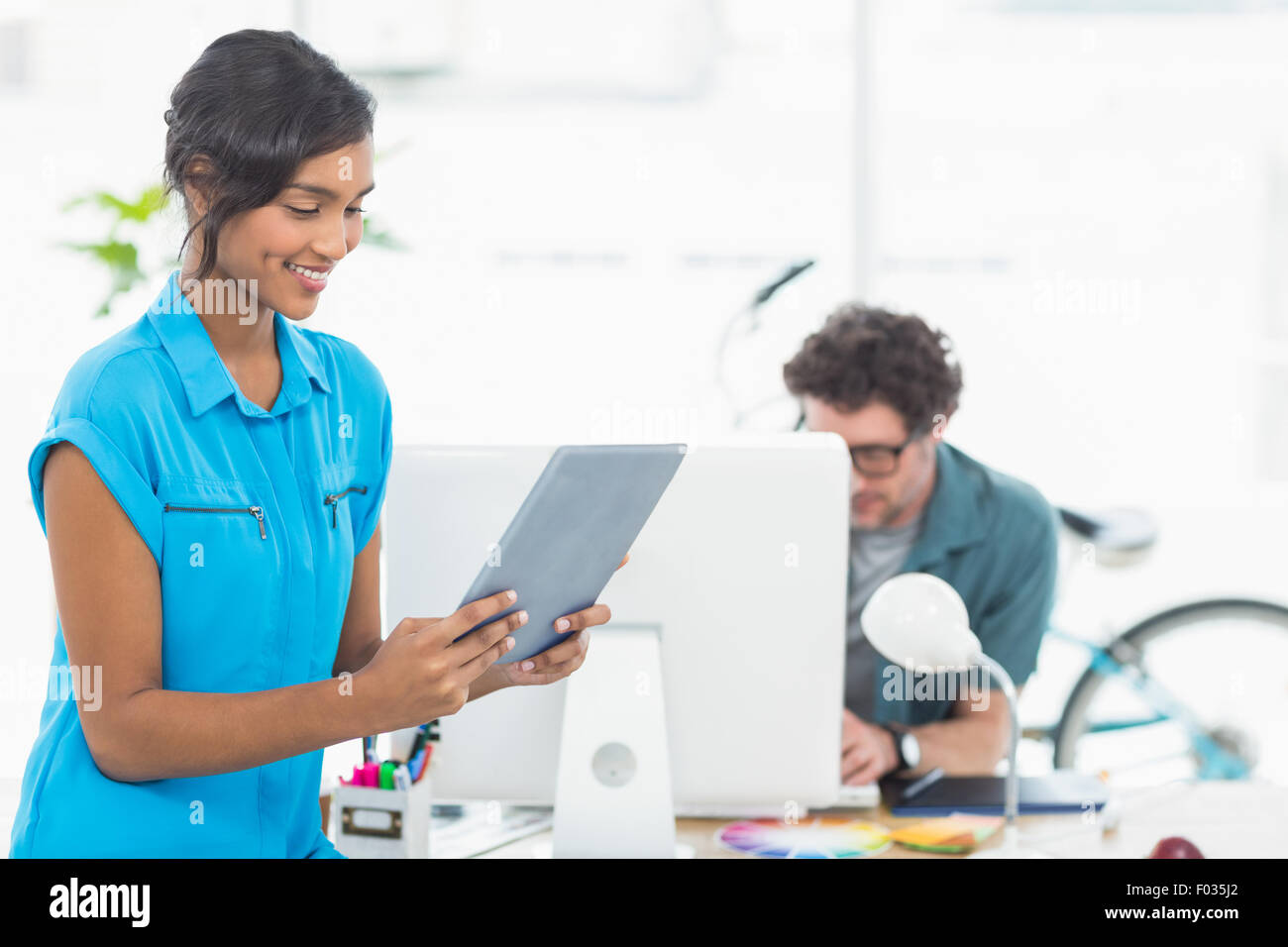 Smiling businesswoman using tablet with colleagues behind Stock Photo ...