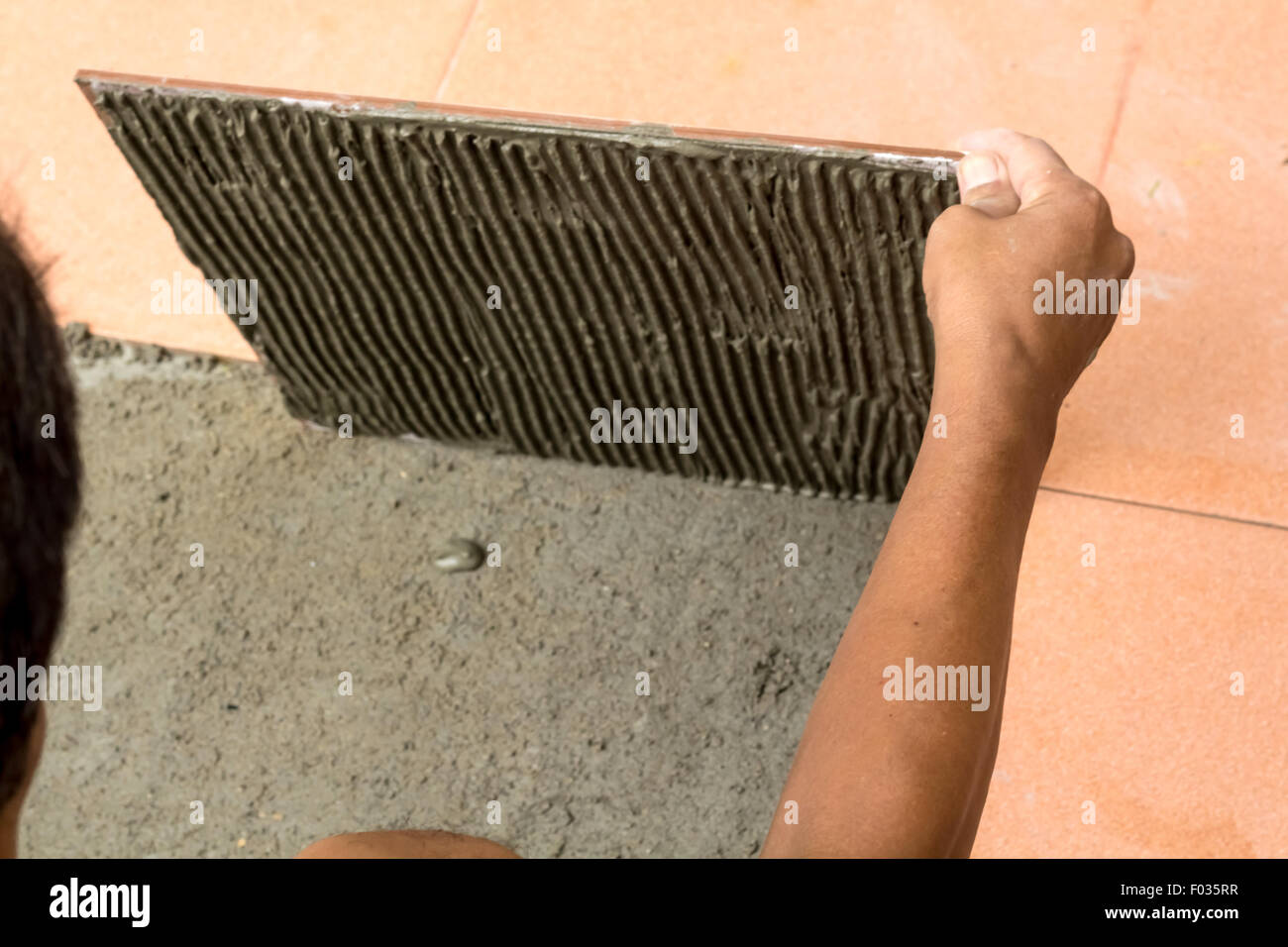 a tiler at work. bonding of floor tile with tile adhesive and filler ...