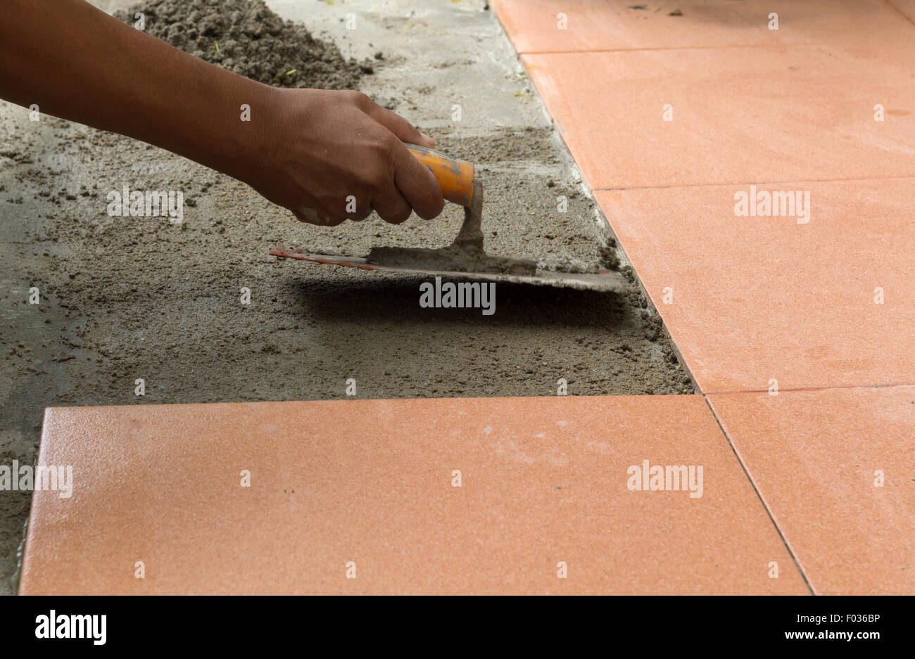 a tiler at work. bonding of floor tile with tile adhesive and filler ...