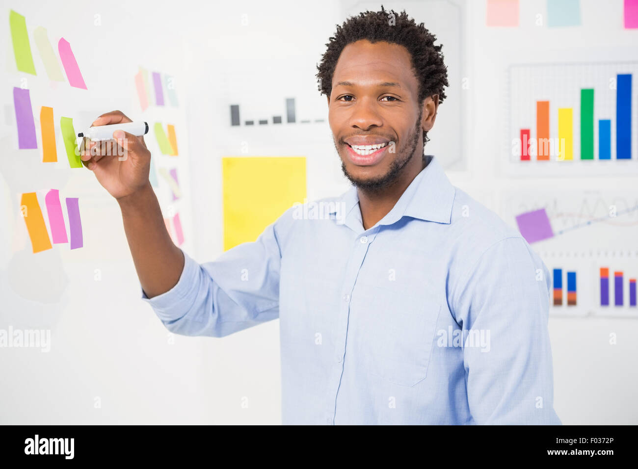 Young smiling businessman writing on sticky notes Stock Photo - Alamy
