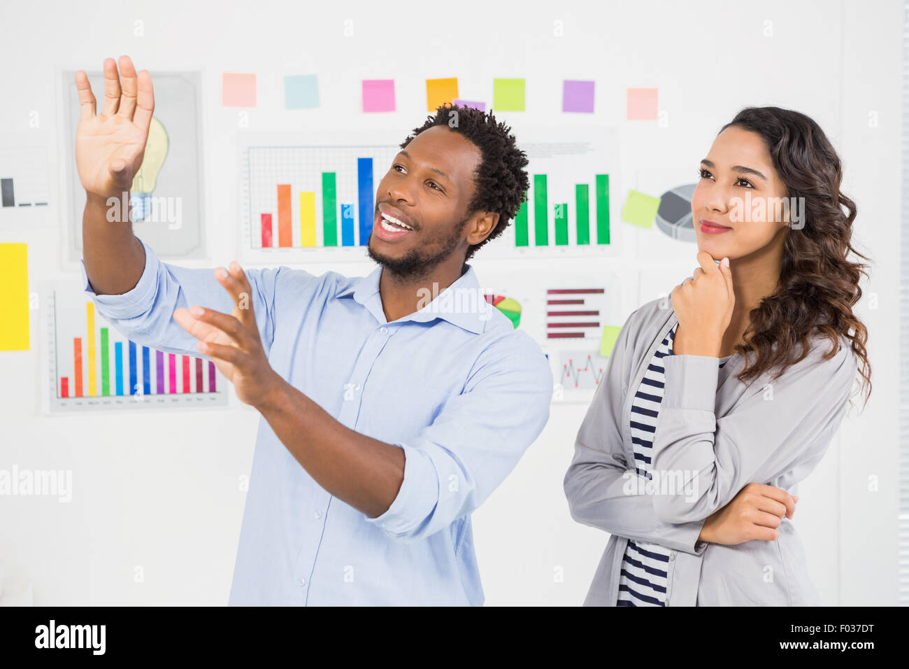 Young creative business people looking and showing something at the ...