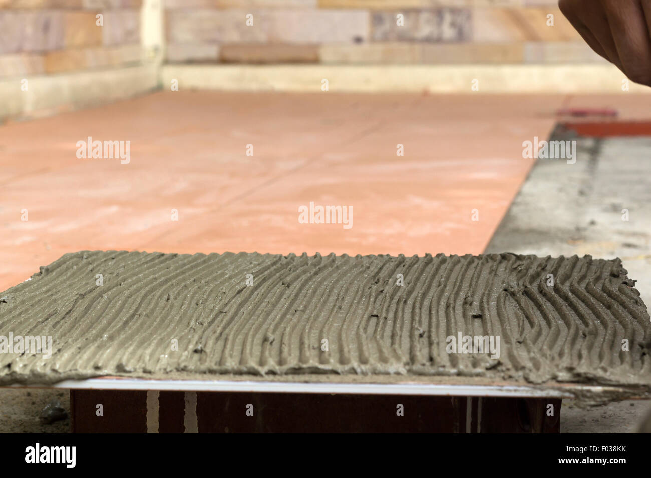 a tiler at work. bonding of floor tile with tile adhesive and filler ...