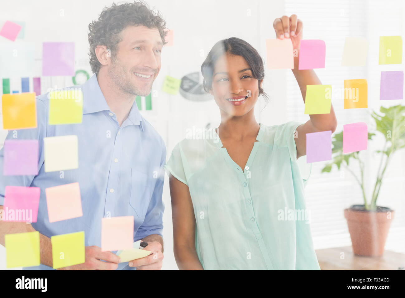 Puzzled business team looking post its on the wall Stock Photo - Alamy